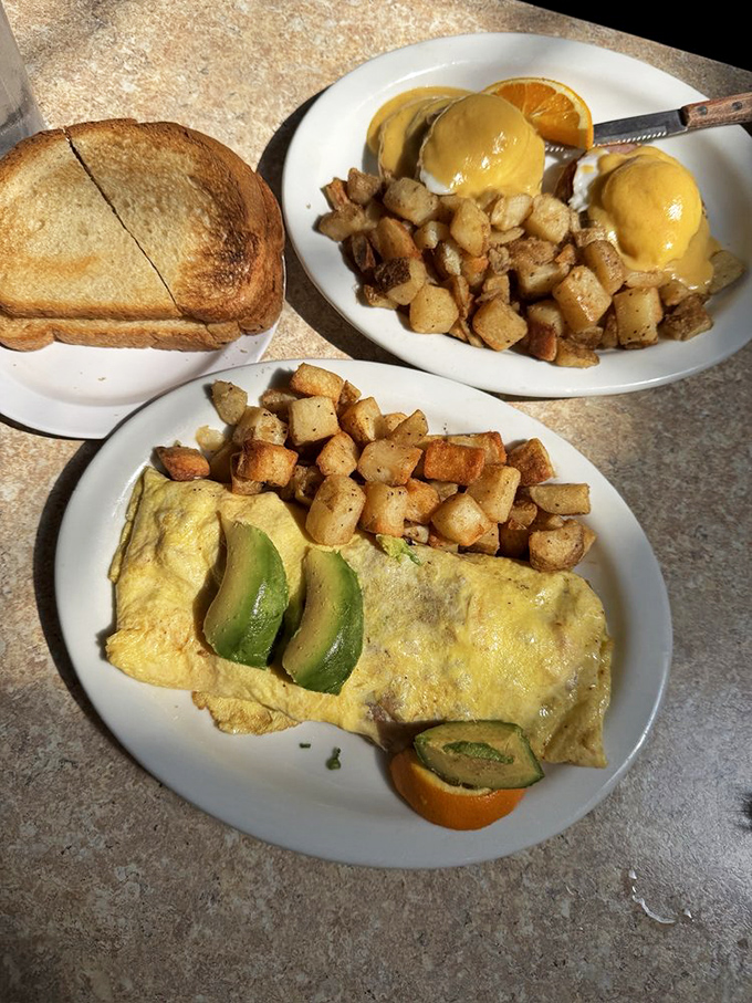 An omelet and eggs Benedict locked in a delicious standoff. The avocado-topped creation whispers, "You made the right choice coming here today."