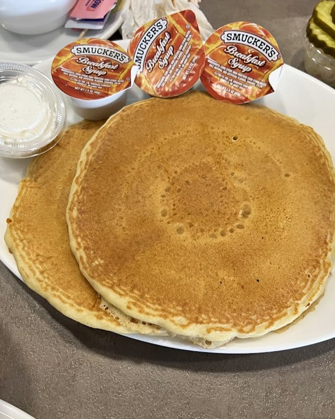 Pancakes so perfectly golden they belong in Fort Knox. Those Smucker's syrup cups stand ready for their ceremonial pouring ritual.