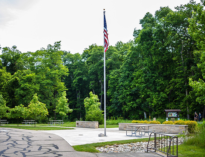 The preserve entrance welcomes visitors with classic park amenities: picnic tables, flagpole, and the promise of adventure just beyond the trees.