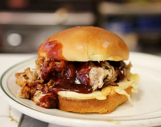 This pulled pork sandwich isn't messing around. Tender meat practically surrendering to gravity, slathered in a sauce that's struck the perfect balance between sweet and tangy.