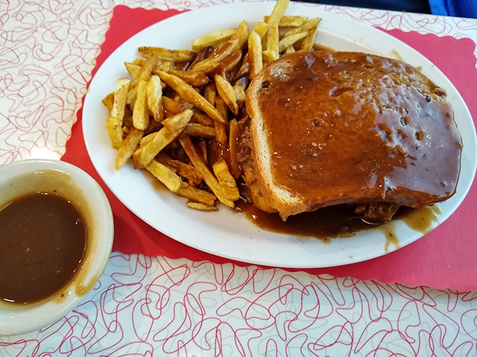 Hot roast beef sandwich swimming in gravy alongside golden fries. When comfort food gets its PhD, this is the dissertation it submits.