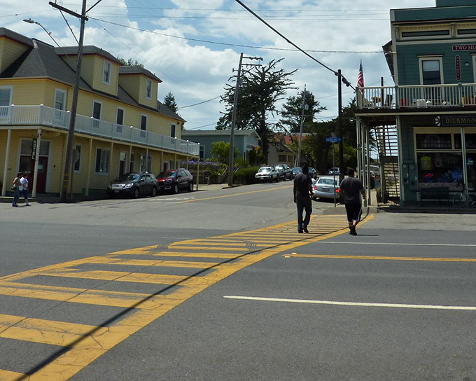 Two pedestrians cross Main Street where traffic jams mean waiting for three cars instead of two. Small-town pace at its most refreshing.