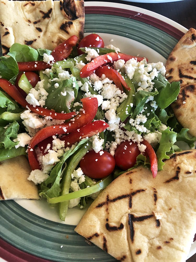 A salad that refuses to be boring: fresh greens, vibrant peppers, and feta cheese surrounded by grilled flatbread—proof that vegetables can have personality too.