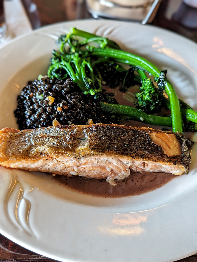 Salmon with crispy skin that crackles like nature's potato chip, accompanied by black lentils that add earthy depth to each bite.