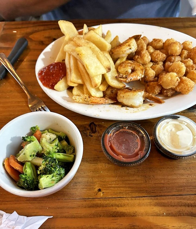 A seafood platter that hits all the right notes&mdash;crispy shrimp, golden fries, and fresh veggies. The holy trinity of coastal dining.