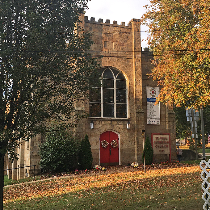 St. Paul Lutheran's stone facade and crimson doors pop against autumn leaves, a postcard-perfect scene straight from small-town central casting.