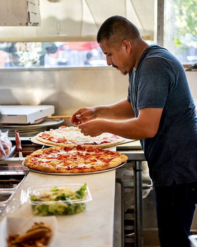 Pizza artistry in action. Behind every perfect slice is someone who understands that dough-tossing is both science and poetry in motion.