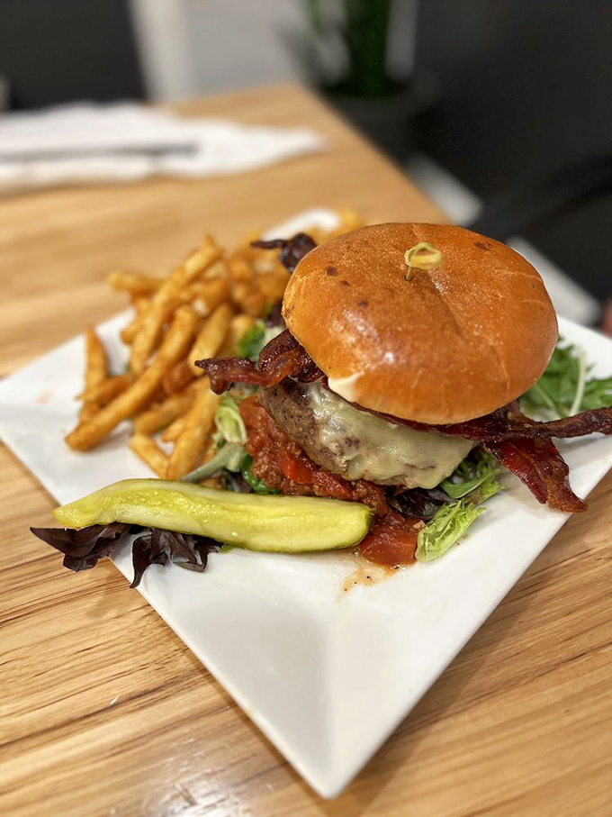 Burger architecture at its finest. A golden brioche bun cradling a juicy patty, crisp bacon, and melted cheese &ndash; with a pickle standing guard against mundane meals.