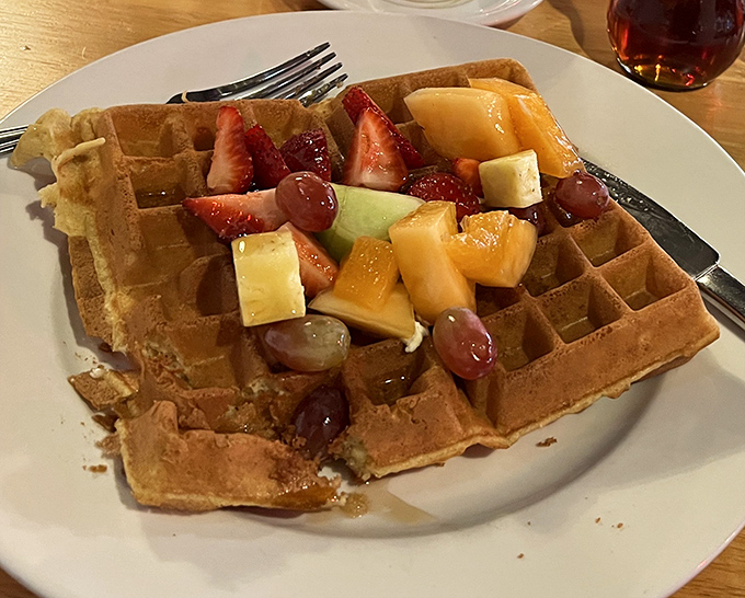 A waffle that's clearly gone to finishing school, dressed in its finest fruit attire and ready to transform your ordinary morning into something special.