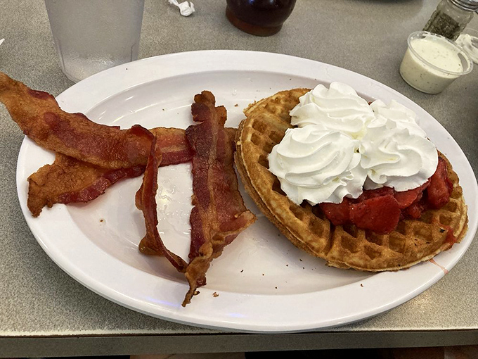Waffles topped with strawberries and whipped cream alongside bacon that's achieved that magical state between chewy and crisp &ndash; breakfast nirvana exists!