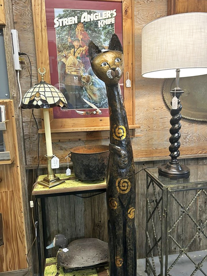 This elongated wooden cat statue isn't just decor&mdash;it's art with attitude, standing guard beside vintage lamps with timeless dignity.