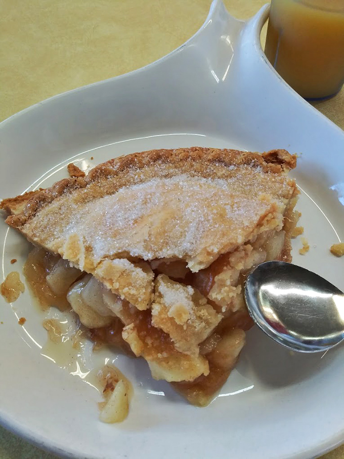 Apple pie that doesn't need Instagram filters to look good. That golden crust shatters just right, revealing tender fruit that's been bubbling away in its own sweet juices.