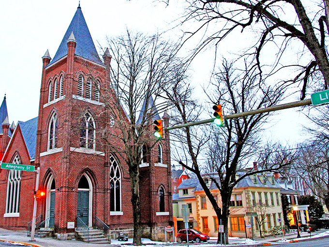 This red brick church stands as both architectural achievement and community anchor, its twin spires reaching skyward like exclamation points.