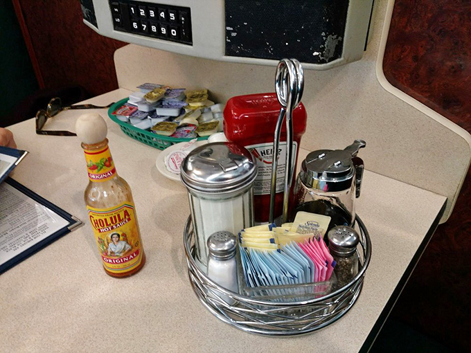 The tabletop essentials: sugar packets arranged like playing cards, classic diner salt and pepper shakers, and hot sauce standing by for emergency flavor situations.