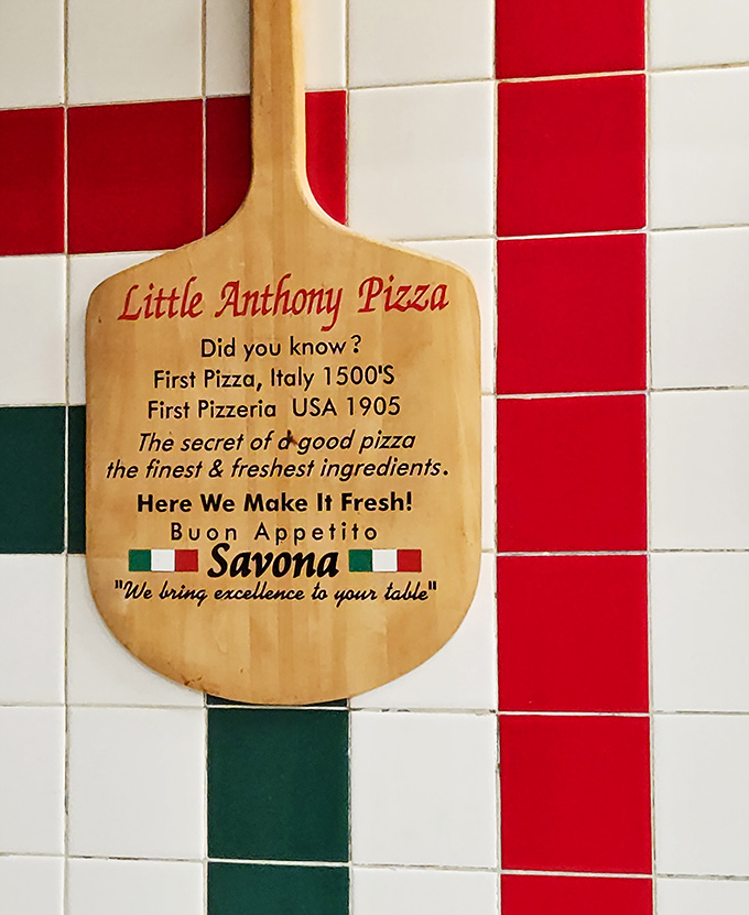 Philosophy carved into wood: "The secret of a good pizza: the finest & freshest ingredients." A decorative pizza peel that doubles as the restaurant's mission statement.