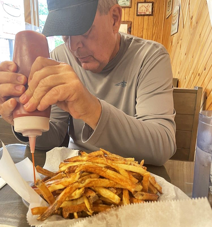 The sacred ritual of condiment application&mdash;this gentleman knows that proper hot dog dressing is serious business requiring full concentration.