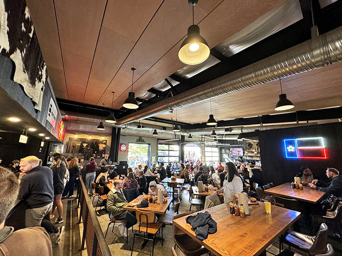 A packed house of happy diners under industrial lighting. The universal language of "mmm" transcends all conversational barriers here.