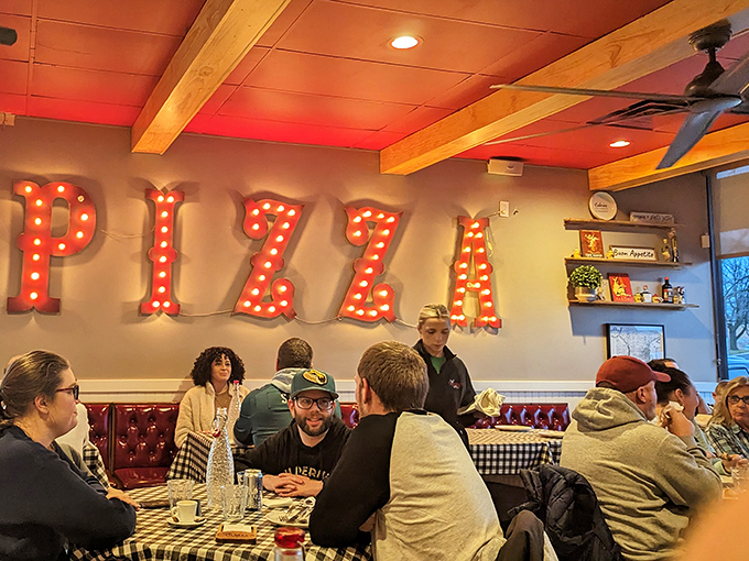 The illuminated PIZZA sign glows like a beacon of hope in a world of mediocre meals. These diners know they've found the real deal.
