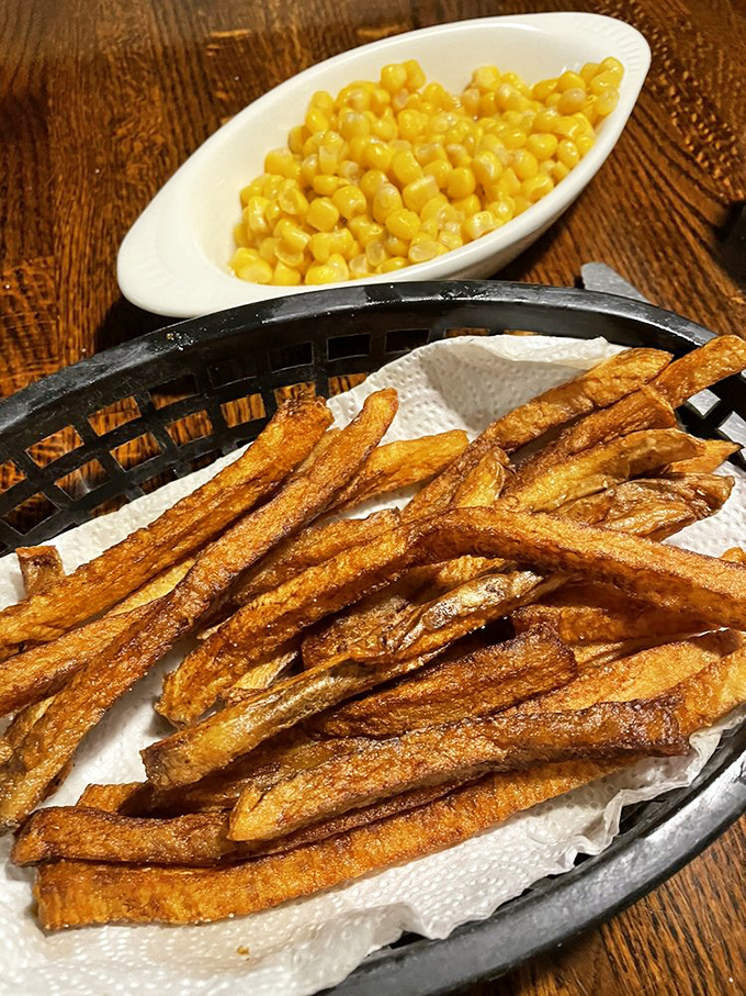 French fries done right – crispy, golden soldiers standing at attention next to sweet corn that gleams like edible sunshine.