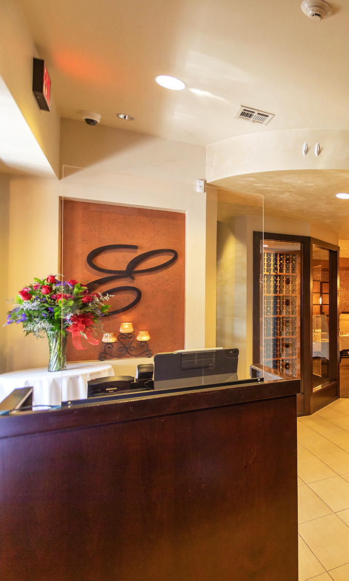 The reception area sets the tone with its elegant "E" monogram, fresh flowers, and the promise of culinary adventures waiting just beyond.