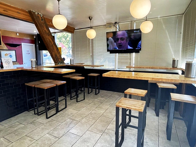 Modern minimalism meets retro charm in this interior view, where wooden stools invite you to perch and contemplate the deeper meaning of perfect fries.