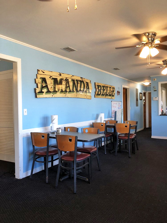 The "Amanda Belle" sign watches over diners like a benevolent seafood guardian. Blue walls and wooden chairs create that "grandma's house meets fishing cabin" vibe.