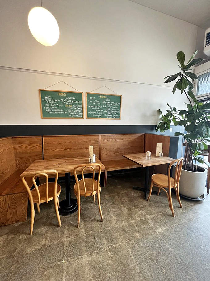 Plants climbing toward sunlight, wooden chairs awaiting conversations, and the promise of deliciousness on those perfectly set tables &ndash; this corner feels like breakfast therapy.