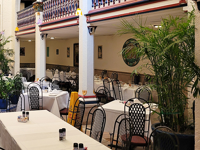 Dining rooms unfold like chapters in a novel, with tropical plants and wrought iron details creating spaces that feel both intimate and grand.