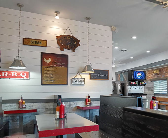 Modern meets traditional with sleek booths, bright red tables, and that pig clock keeping barbecue time on the shiplap wall.