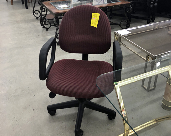 This office chair isn't just furniture &ndash; it's someone's future command center. With its burgundy upholstery still intact, it awaits its next career move.