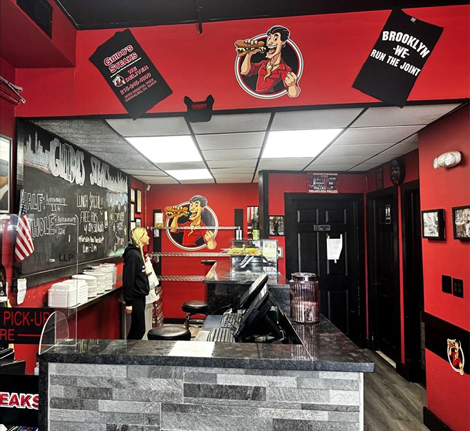 The counter where dreams come true. Red walls, stone facade, and a chalkboard promising "NEW SANDWICHES"&mdash;three syllables that spark joy.