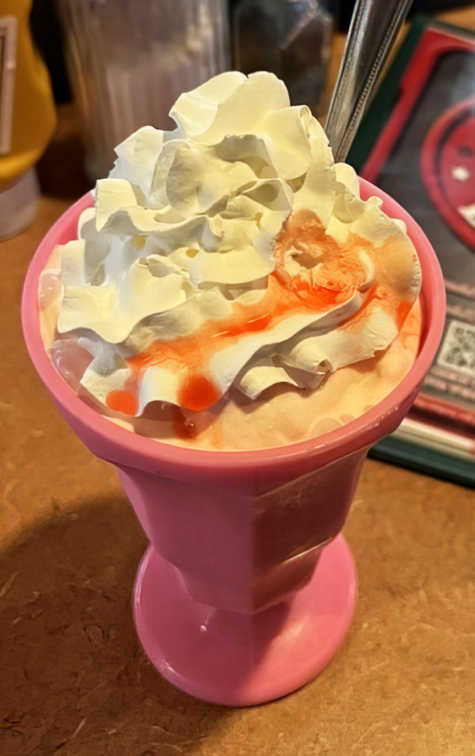 A strawberry shake served in a pink chalice fit for royalty. That swirl of whipped cream and syrup is the crown jewel of any diner experience.