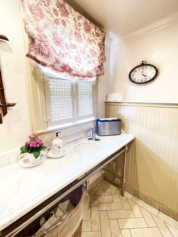 Even the washroom continues the cottage charm story, with floral curtains and marble countertops that feel more home than restaurant.
