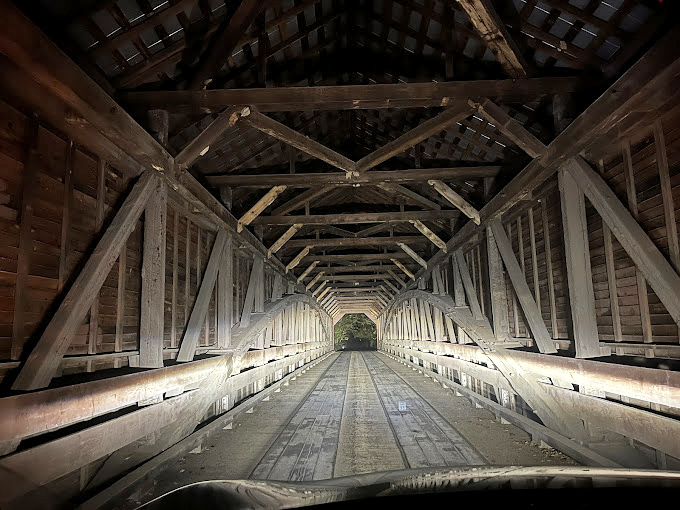 Nighttime transforms the interior into a mesmerizing tunnel of shadows and light, each wooden beam standing sentinel in the darkness.
