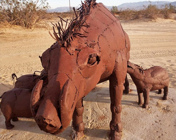 This family of wild boars, crafted from weathered metal, huddles together in the sand&mdash;proof that even in art, there's strength in numbers.
