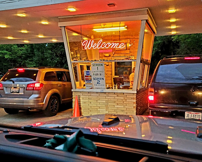"Welcome" glows in neon at the ticket booth, the gateway to an evening of nostalgic movie magic.