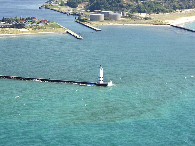 Frankfort: Aerial drama where the channel cuts through golden shores. That lighthouse is the cherry on top of this water sundae.
