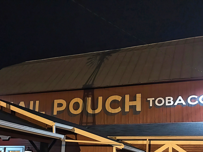 The iconic Mail Pouch Tobacco sign illuminates the night, a beacon for hungry travelers seeking refuge from ordinary dining experiences.