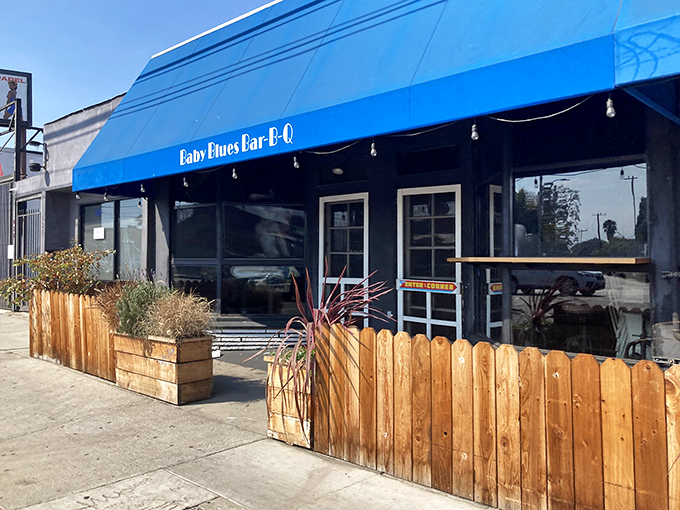 That iconic blue awning and wooden fence might not scream "barbecue mecca," but your nose will know the truth before you even reach the door.