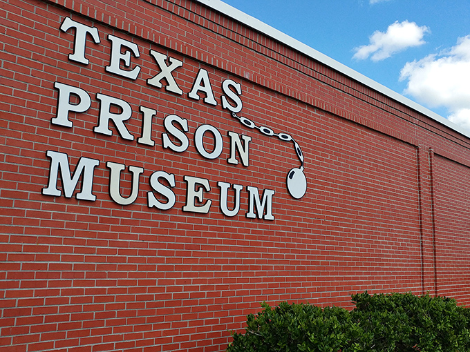 The bold white letters against red brick announce your arrival at a place where Texas history takes its most sobering turn.