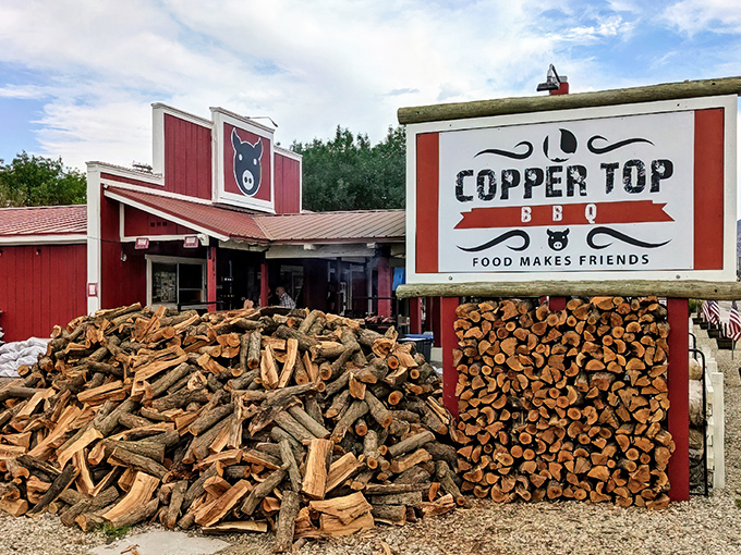 The iconic red exterior of Copper Top BBQ, stacked high with firewood, hints at the smoky magic waiting inside.