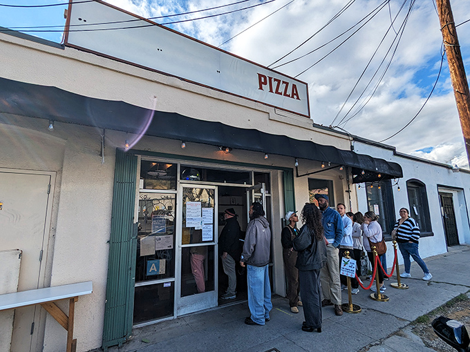 The unassuming storefront with "PIZZA" proudly displayed above might not look like much, but that line of people knows something you should too.