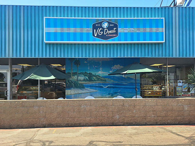 The ocean mural whispers "beach town bakery" while those umbrellas promise the perfect spot for donut meditation.