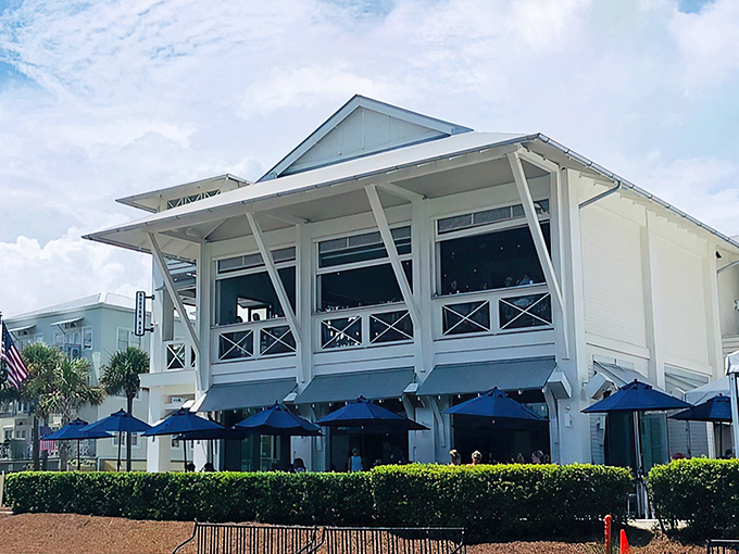 Coastal elegance meets laid-back charm at Shunk Gulley's pristine white exterior, where those blue umbrellas practically whisper "come sit a while."