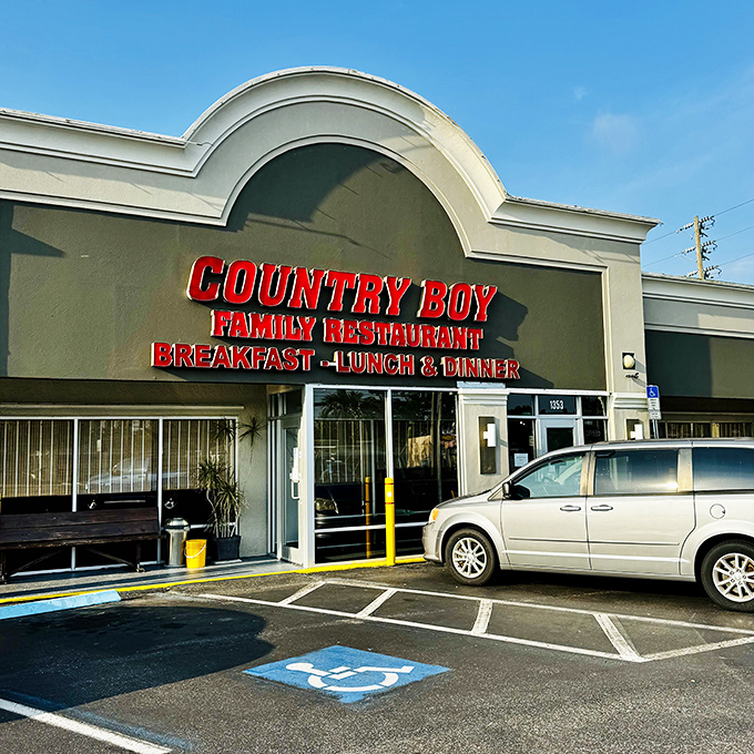 The bright red signage of Country Boy Restaurant stands out like a beacon for hungry travelers, promising homestyle meals without pretension.