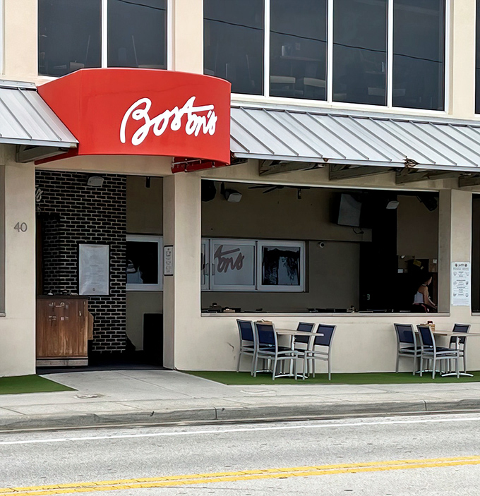 The iconic red awning of Boston's on the Beach beckons like a lighthouse for hungry souls, promising New England comfort in the heart of Delray.