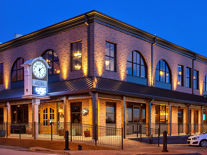 The iconic brick exterior of Bare Bones Steakhouse glows at twilight, its distinctive clock tower standing sentinel over downtown Buford like a beacon for hungry travelers.