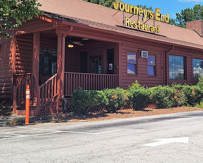 The rustic log cabin exterior of Journey's End beckons like an old friend, promising comfort food and Southern hospitality beneath that iconic yellow sign.