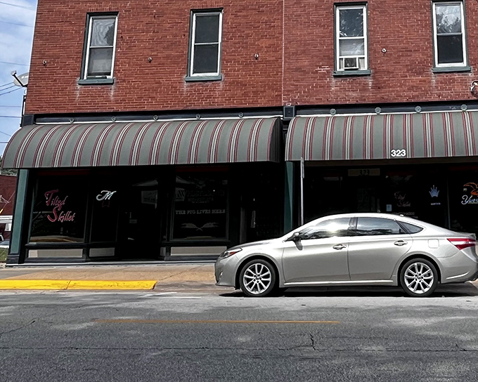 The unassuming brick exterior of The Tilted Skillet hides culinary treasures within. Like all great food stories, this one begins behind a modest striped awning.