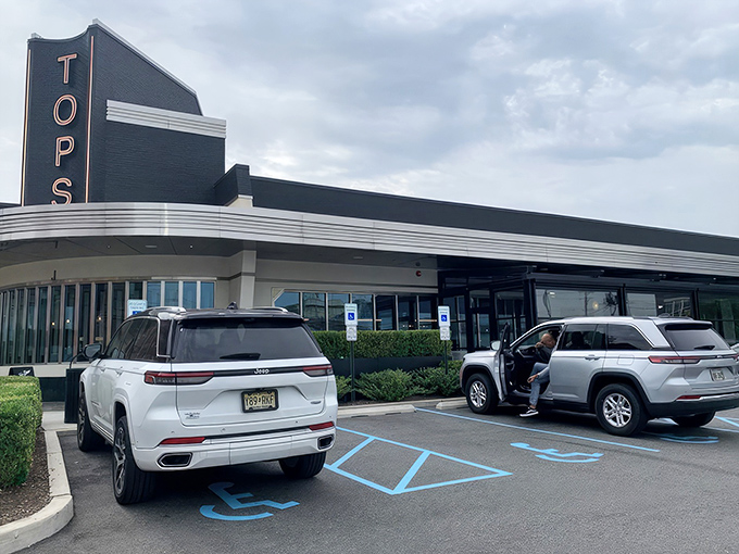 A couple of cars are parked outside a retro-style diner with the sign "TOPS" on the building.